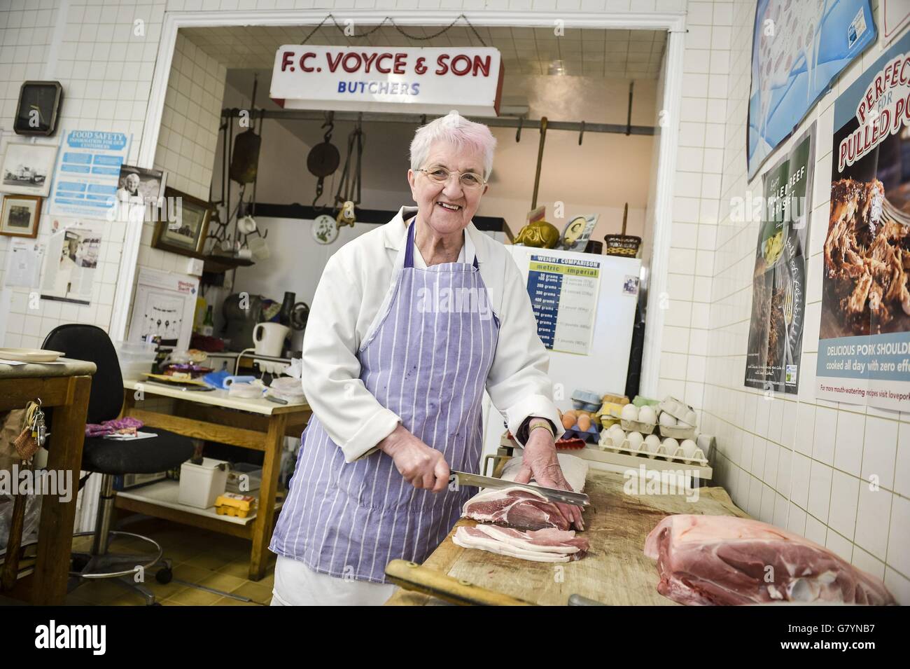Britain's oldest female butcher Marian Voyce cutting bacon in her shop ...