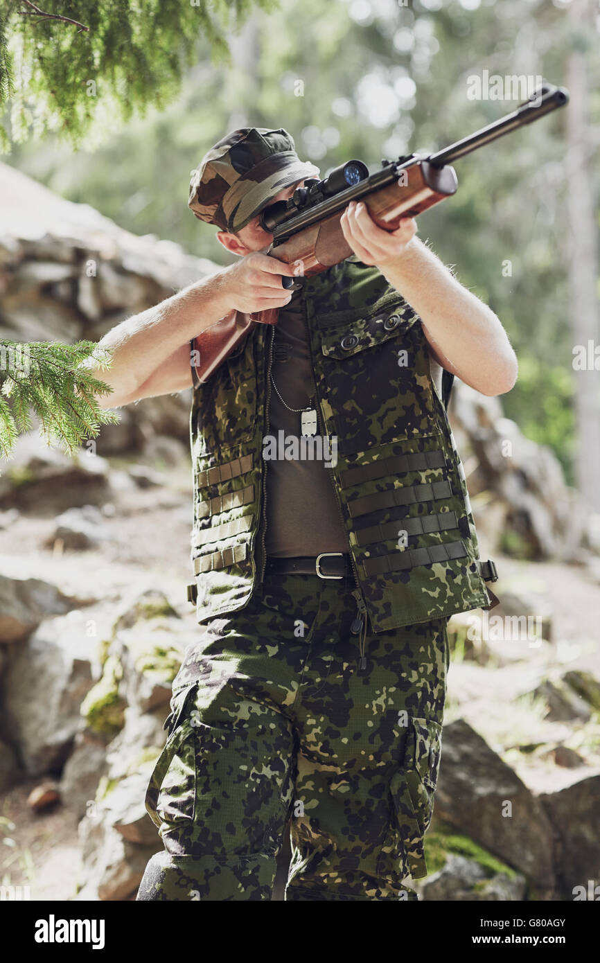 soldier or hunter shooting with gun in forest Stock Photo - Alamy