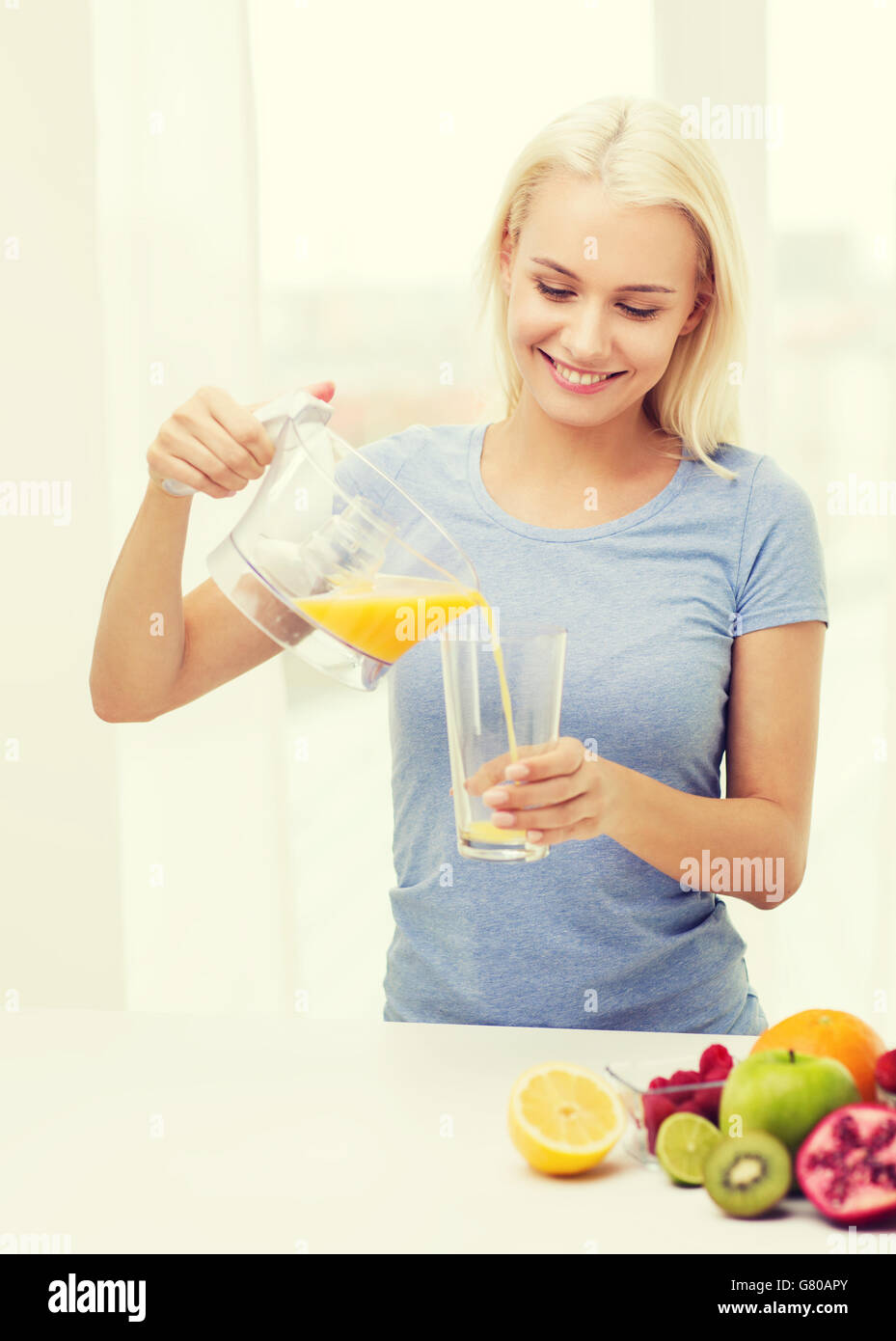 smiling woman pouring fruit juice to glass at home Stock Photo - Alamy