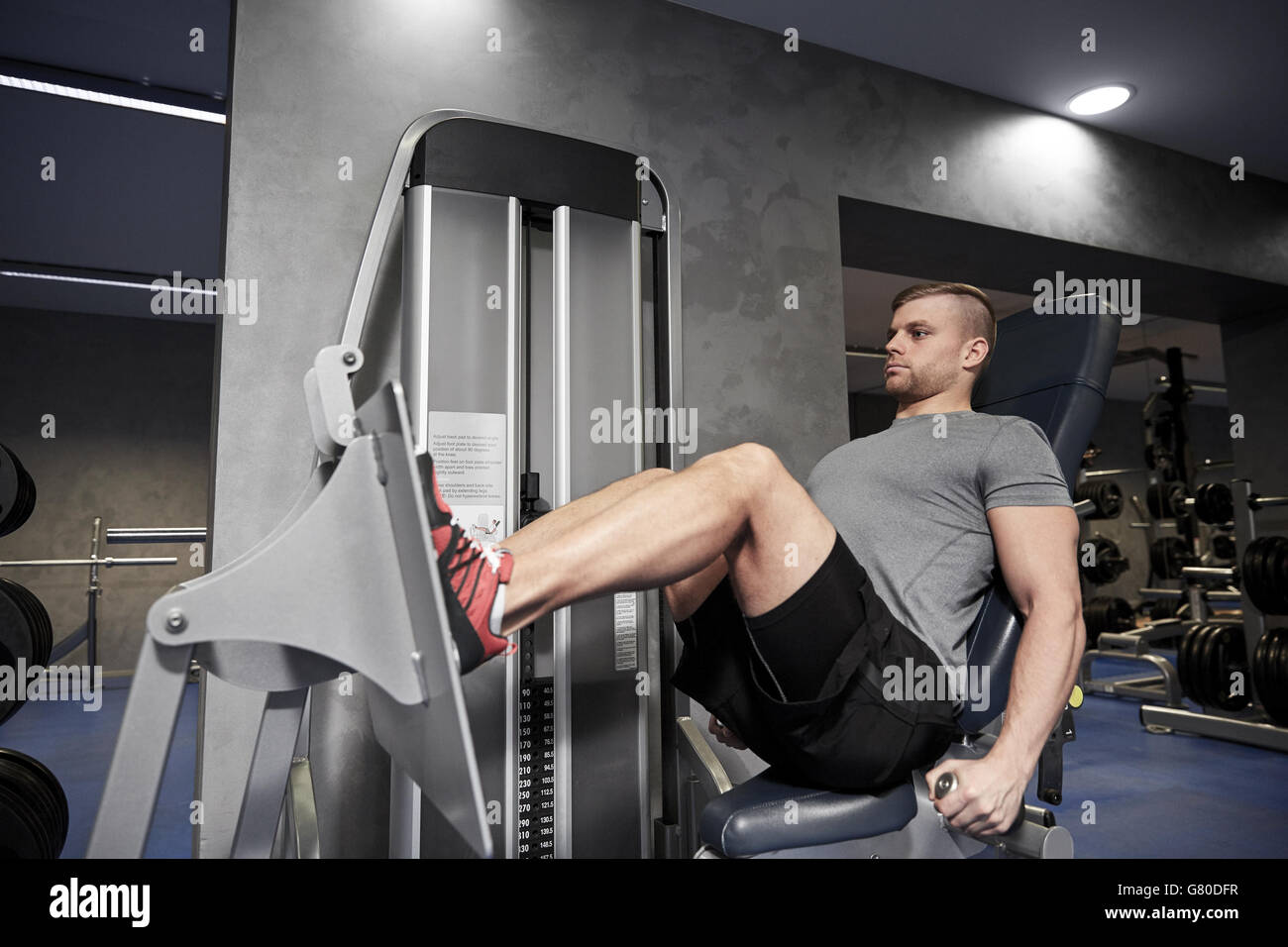 man flexing leg muscles on gym machine Stock Photo - Alamy