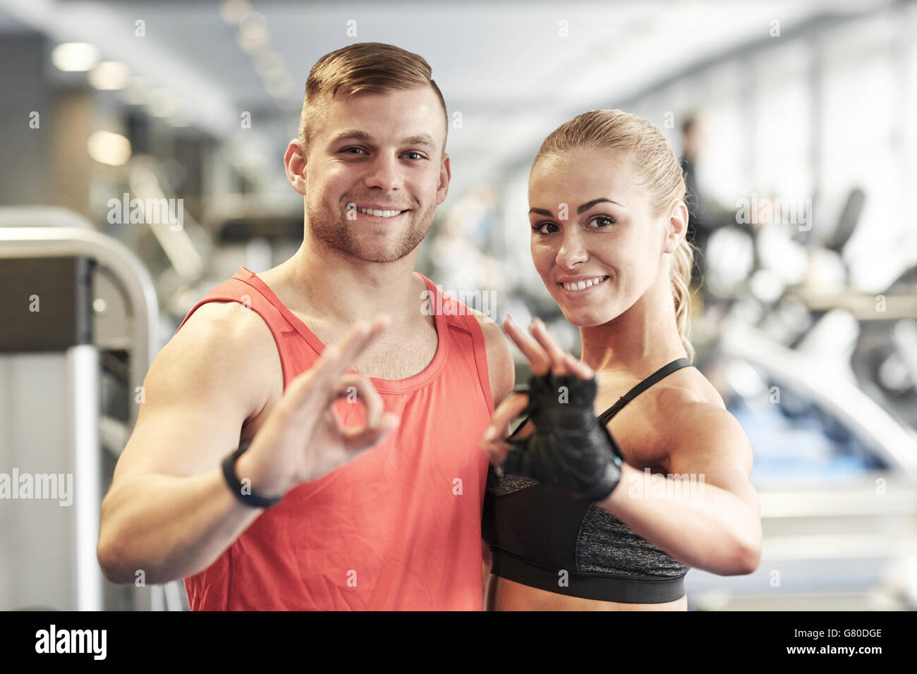 smiling man and woman showing ok hand sign in gym Stock Photo - Alamy