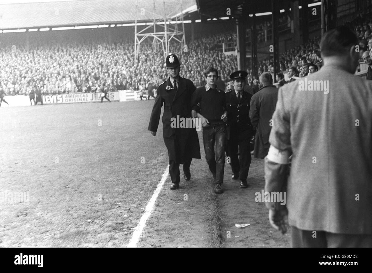 A spectator leaves the crowd "arm in arm" with a police escort at Queen ...