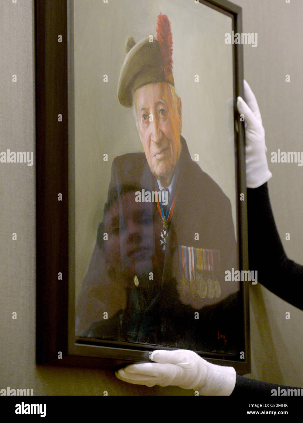 A gallery assistant adjusts a painting of Captain Brian Stewart by Paul ...