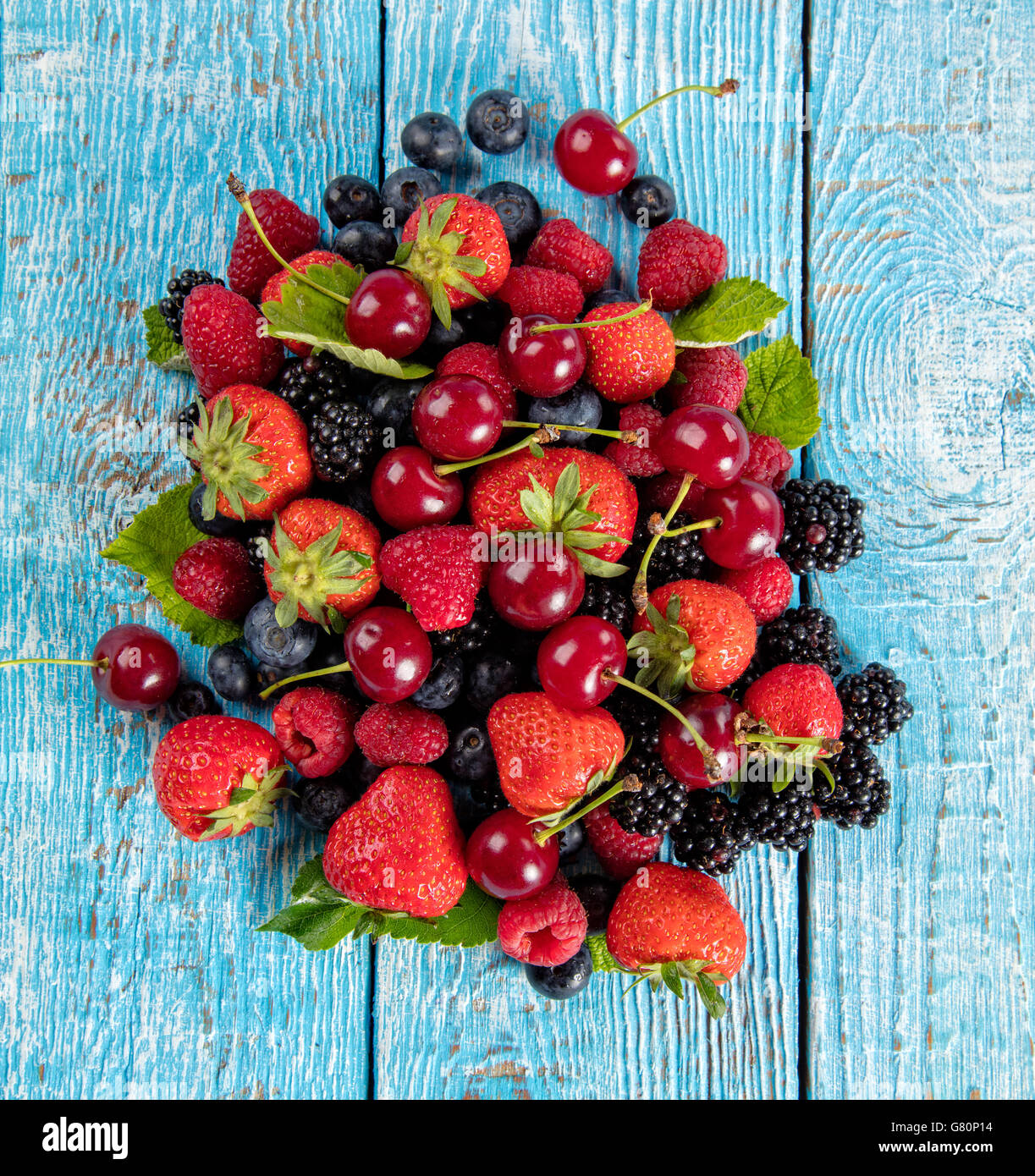 Fresh berry fruit pile with leaves placed on old wooden planks. Shot ...