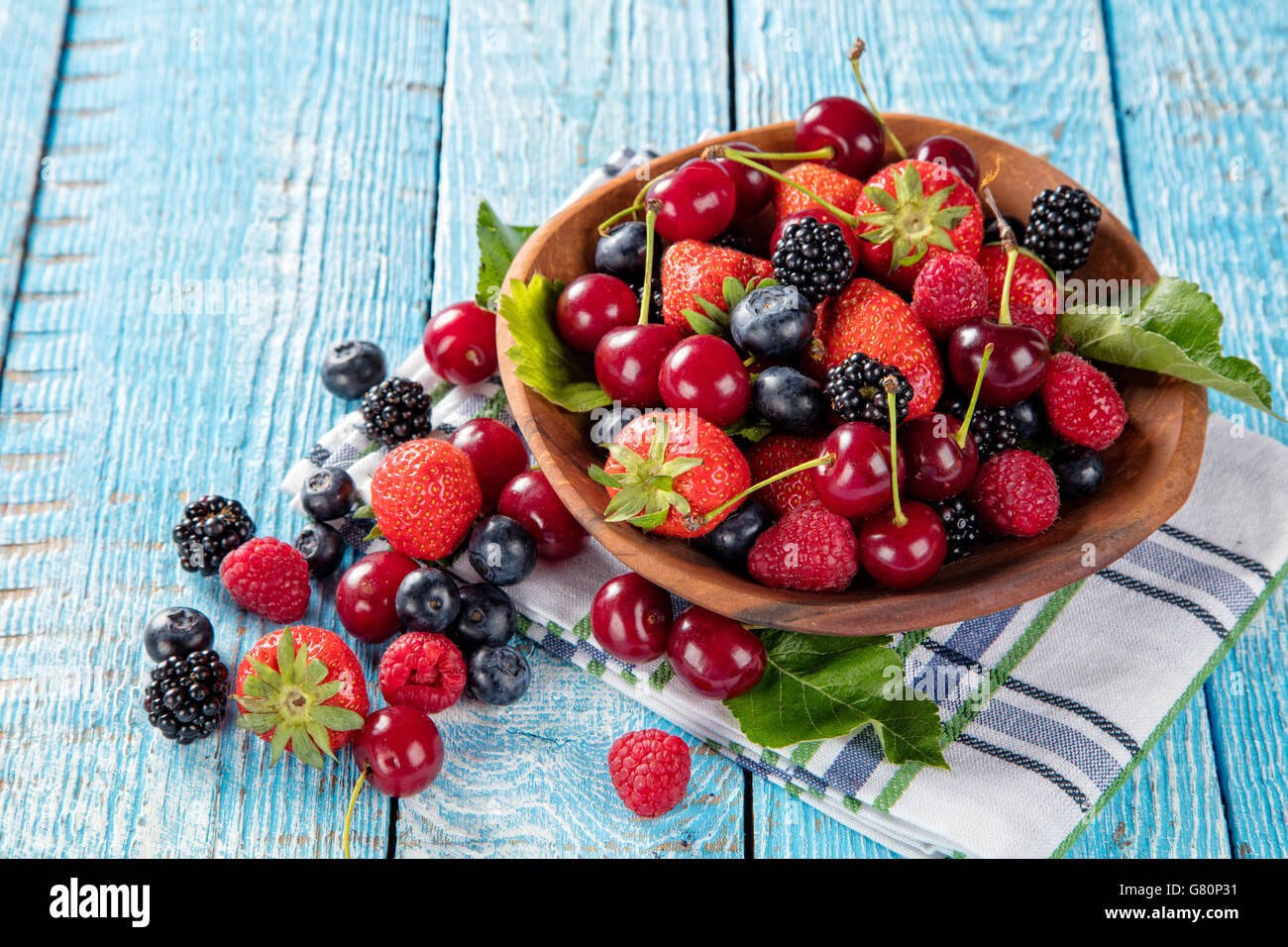 Fresh berry fruit pile in bowl with leaves placed on old wooden planks ...