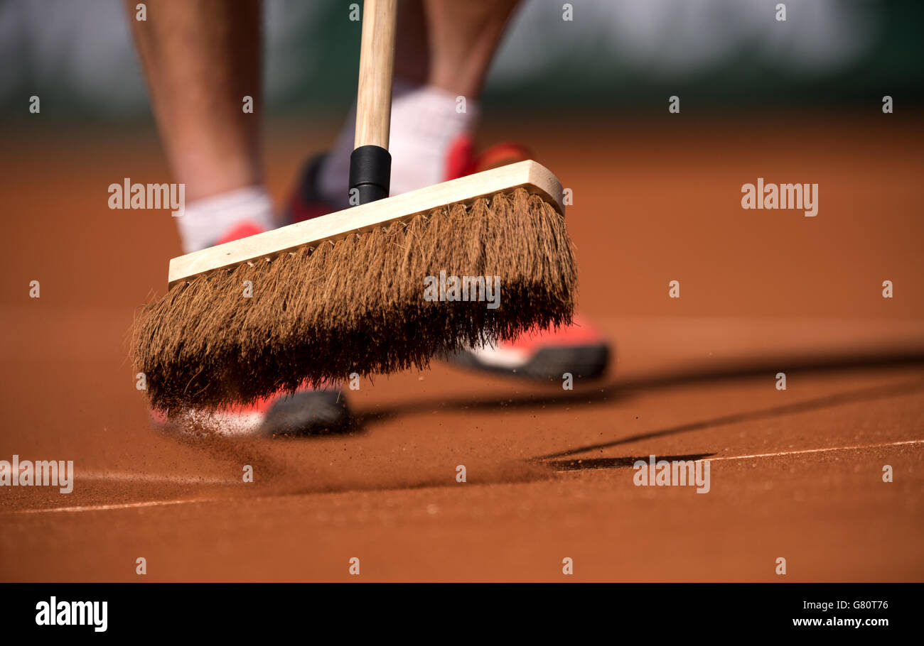A member of the ground staff sweeps the clay off the lines of the court ...