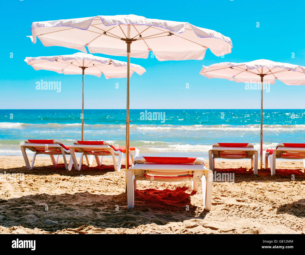 some colorful orange sunloungers and some white umbrellas in a quiet ...