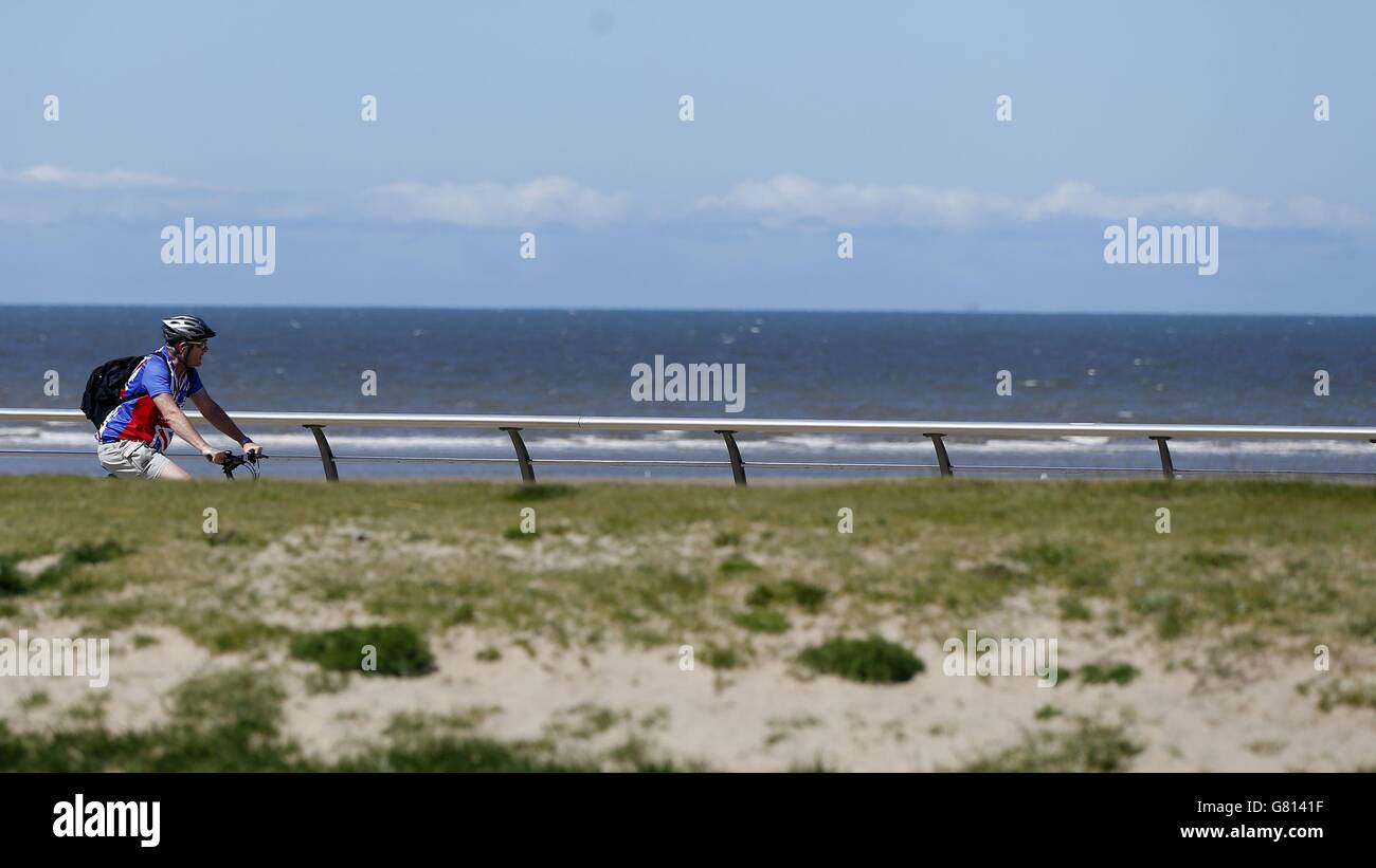 A man cycles along the front in windy conditions on the beach in ...