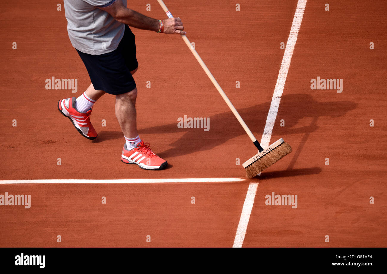 A member of the ground staff sweeps the court on day four of the French ...