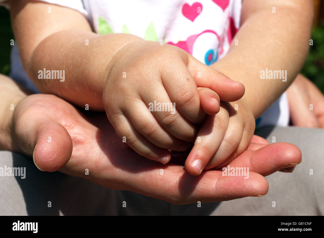 Women's hand holding little baby' hands Stock Photo - Alamy