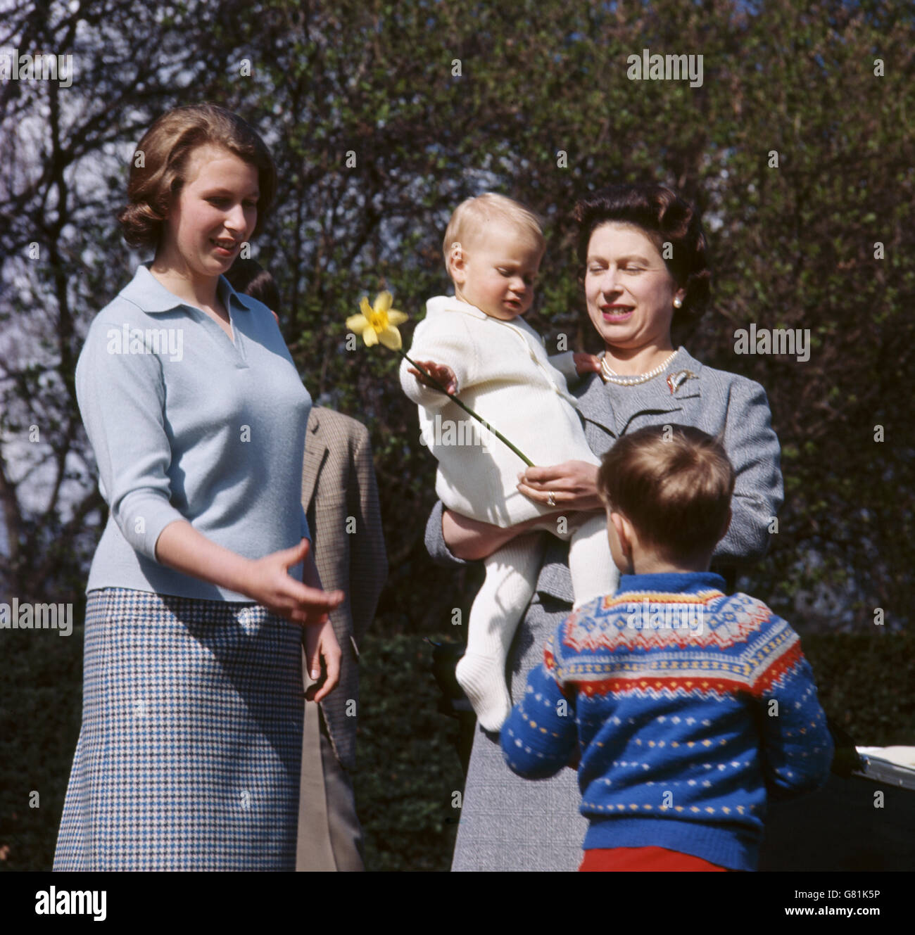Baby Prince Edward holds a daffodil while being carried by the Queen in ...