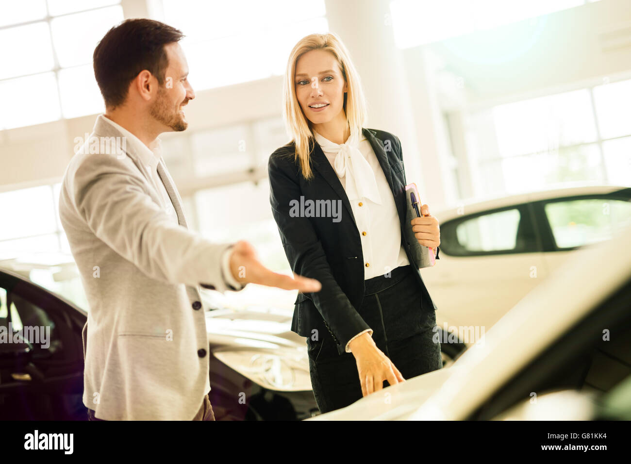 Salesperson showing vehicle to potential customer in dealership Stock ...