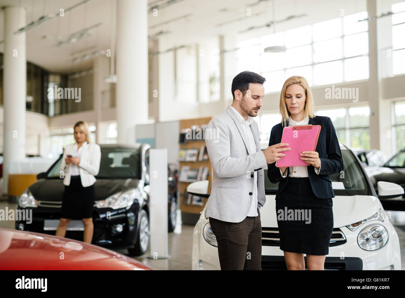 Elegant salesperson working at car dealership Stock Photo - Alamy