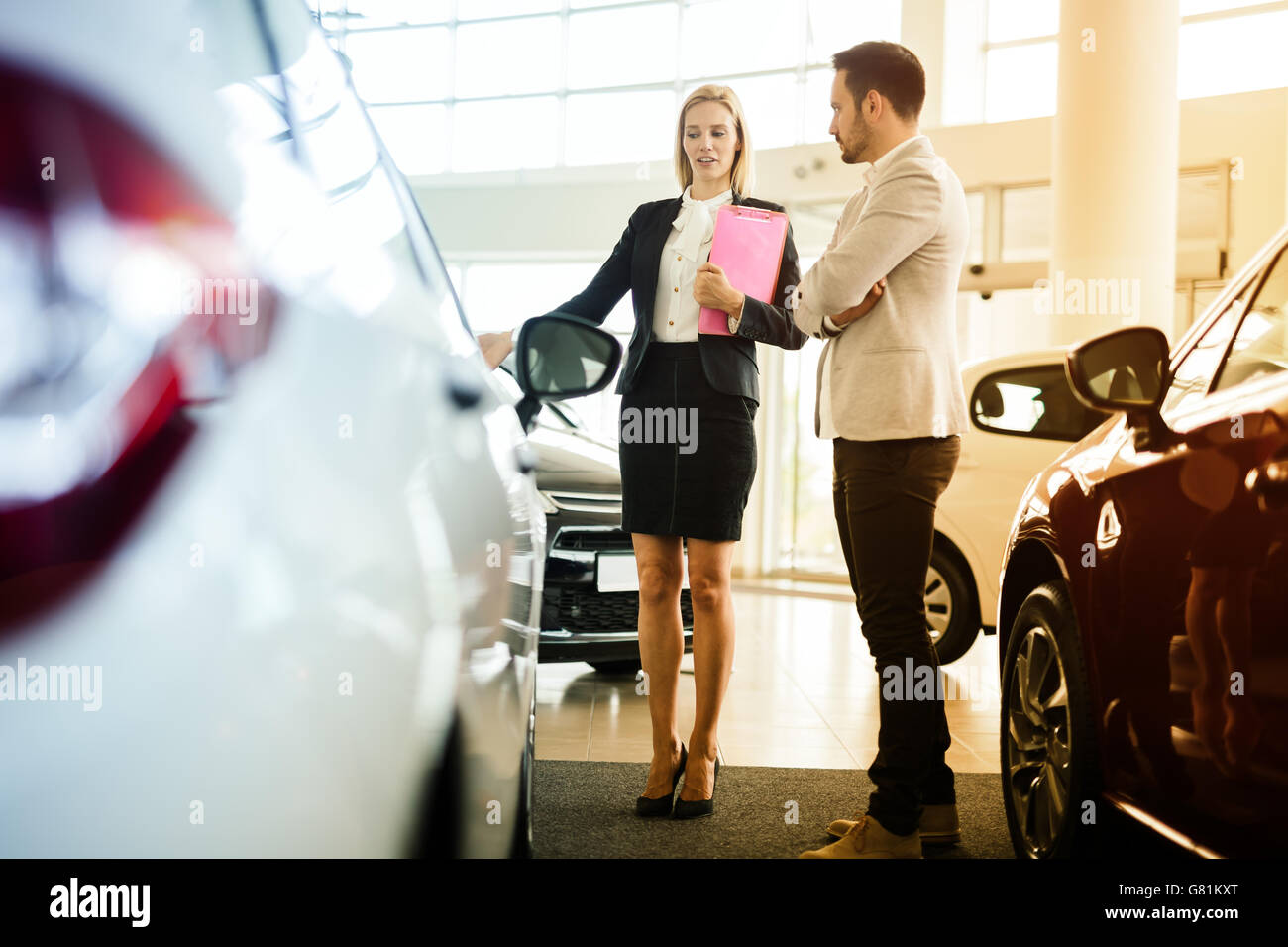 Car salesperson assisting customer at car dealership Stock Photo - Alamy