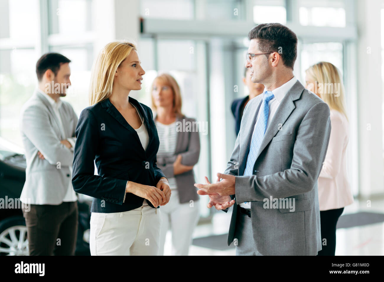 Customer looking at cars at dealership and talking to salesperson Stock ...