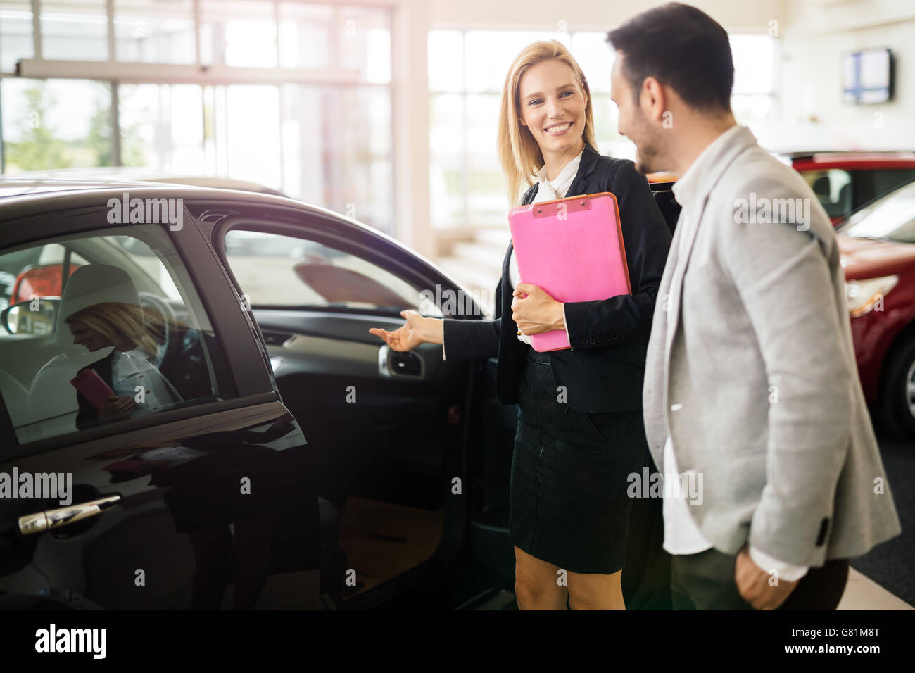 Elegant salesperson working at car dealership Stock Photo - Alamy