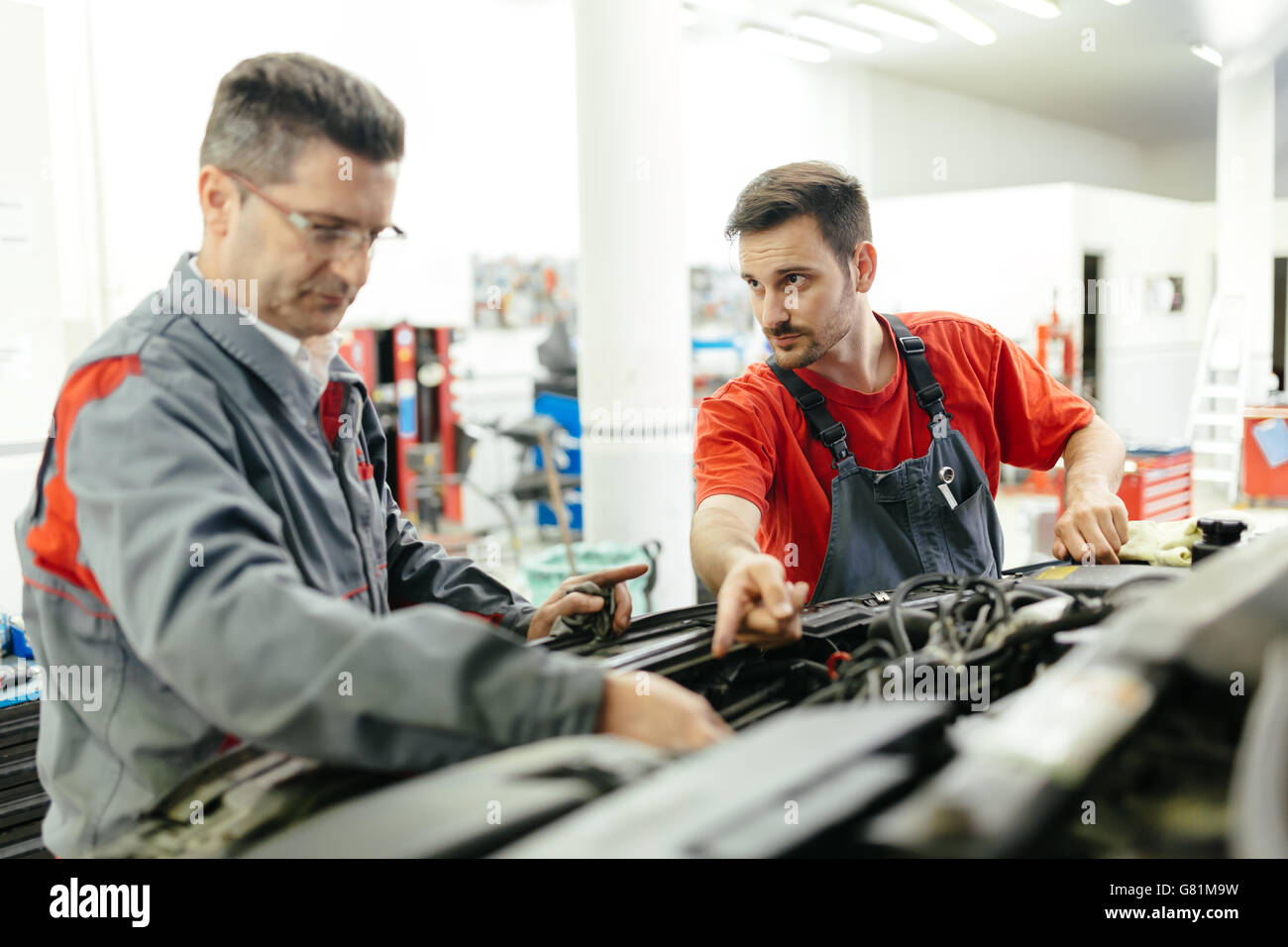Car mechanics fixing car in garage - teamwork Stock Photo - Alamy