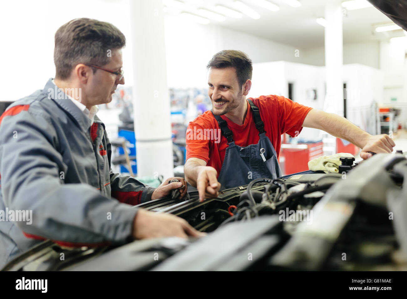 Car mechanics fixing car in garage - teamwork Stock Photo - Alamy