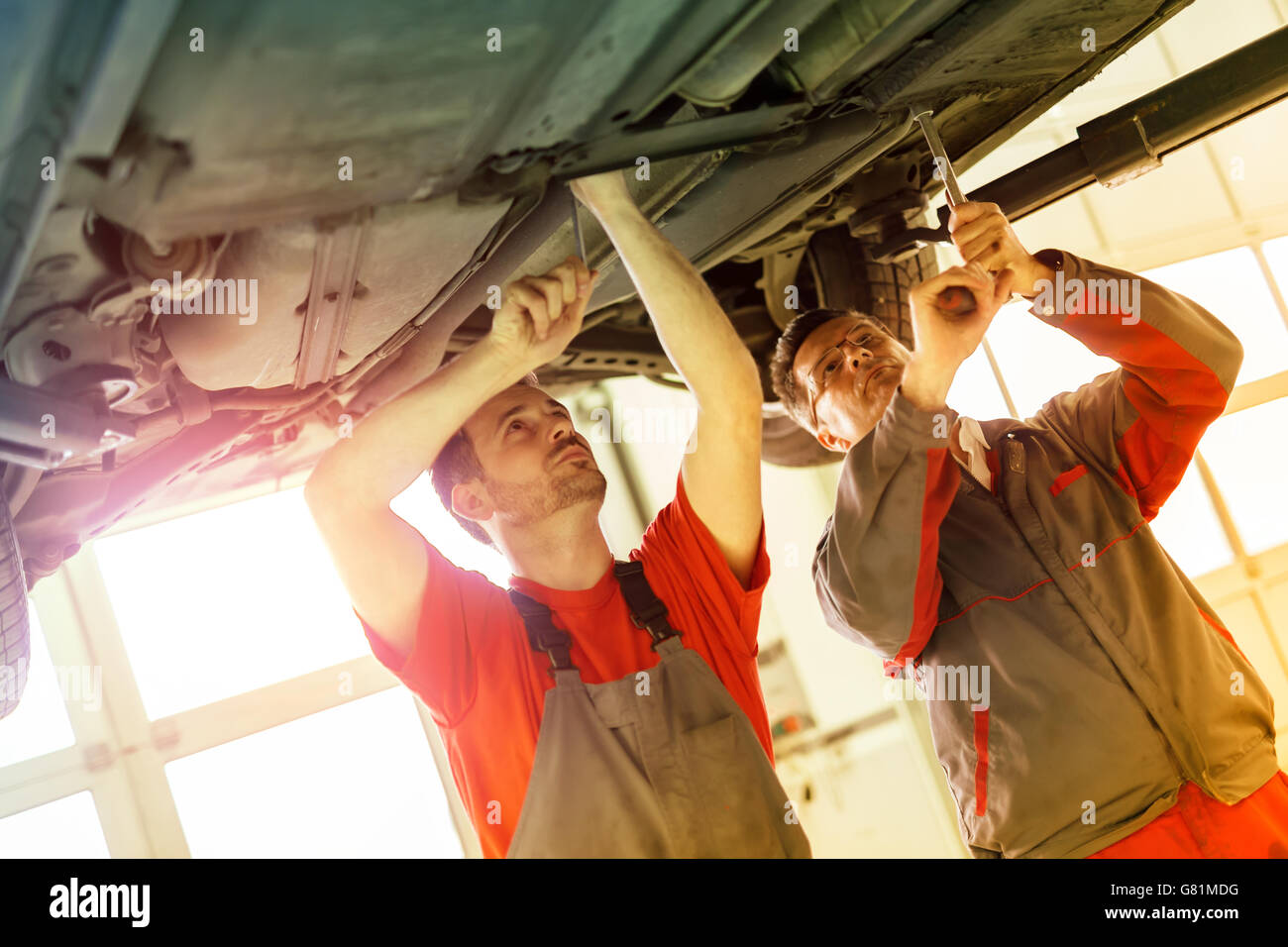 Car mechanics fixing car in garage - teamwork Stock Photo - Alamy