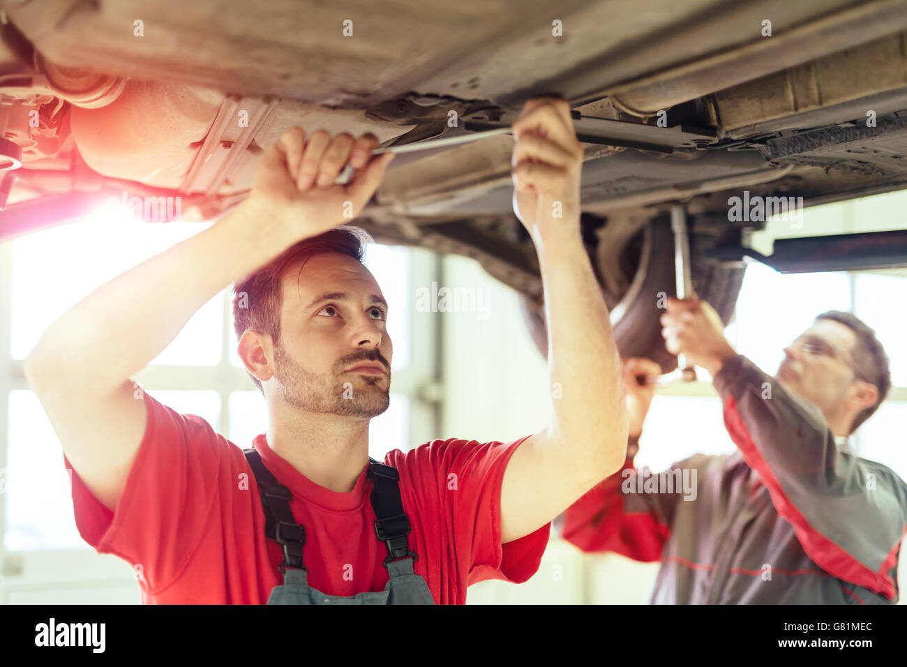 Car mechanic fixing a car in garage at dealership Stock Photo - Alamy