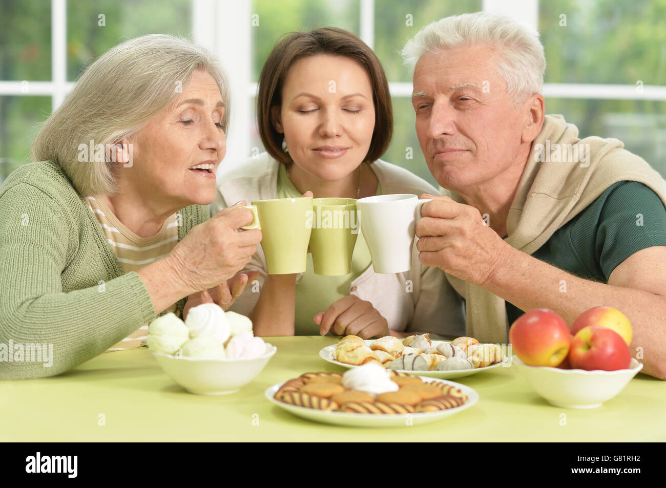 daughter with senior parents drinkig tea Stock Photo - Alamy