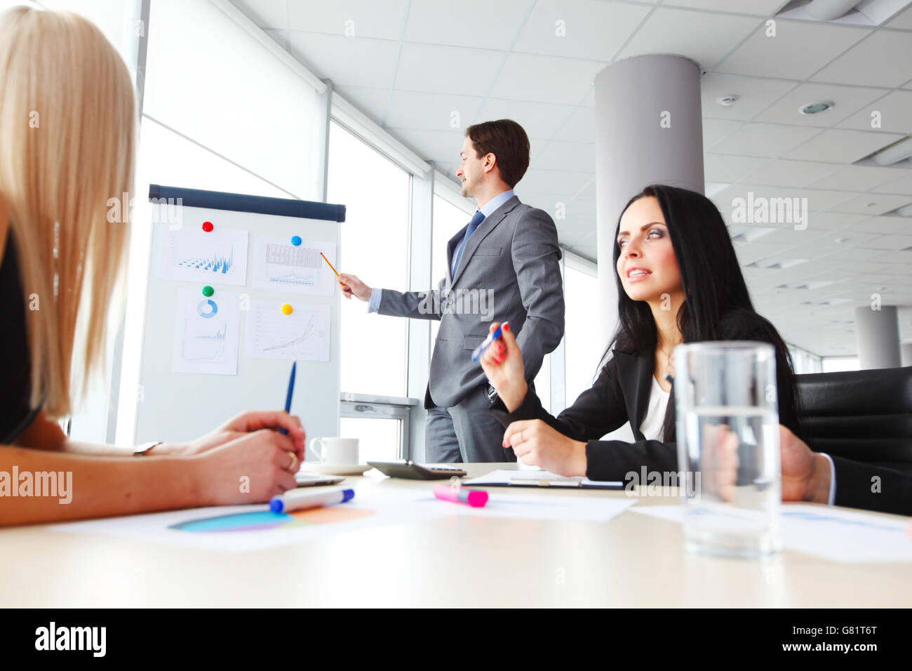 Workers at business meeting looking at presentation of financial ...