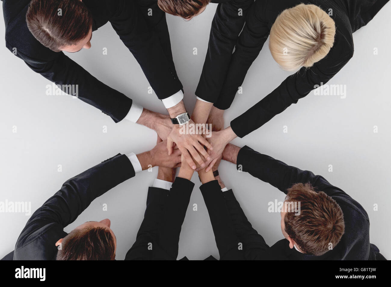 Business team stacking hands sitting around white table Stock Photo - Alamy