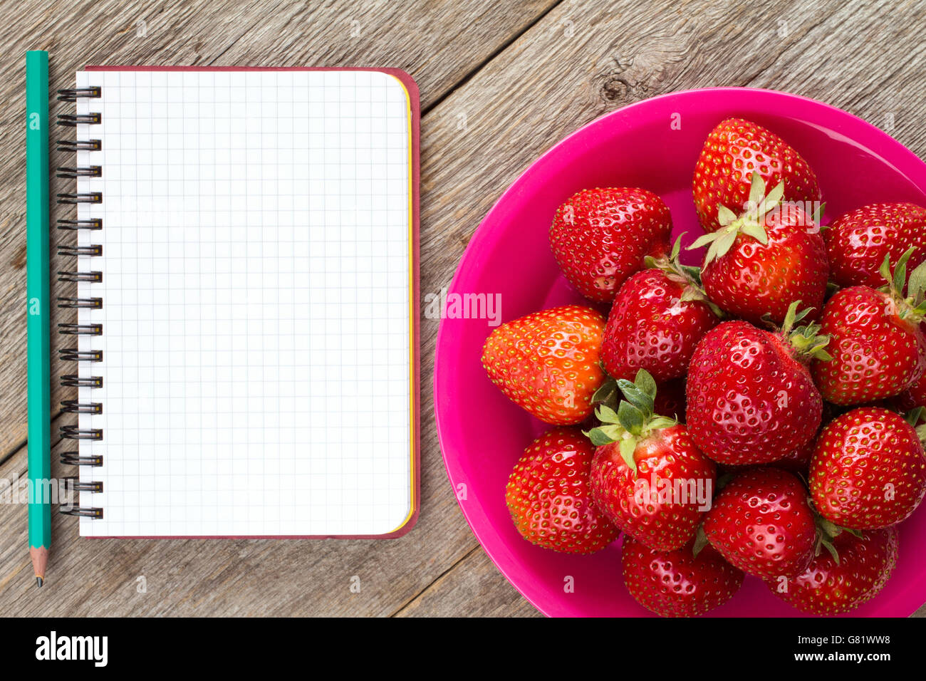 Pink plate with strawberries and blank notebook with pencil Stock Photo ...