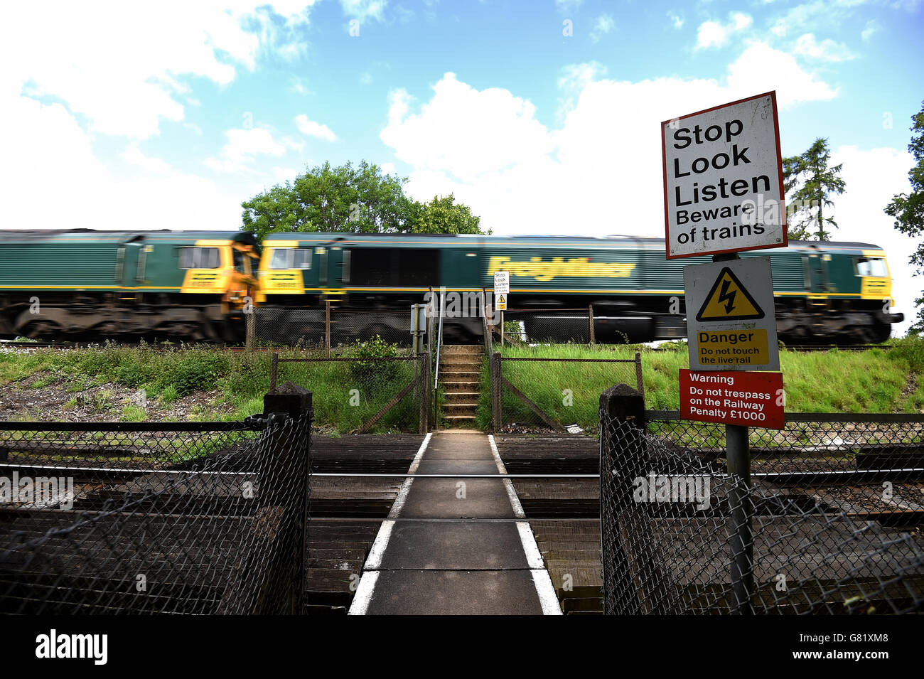 A freight train makes it's way along the tracks next to a Footpath ...