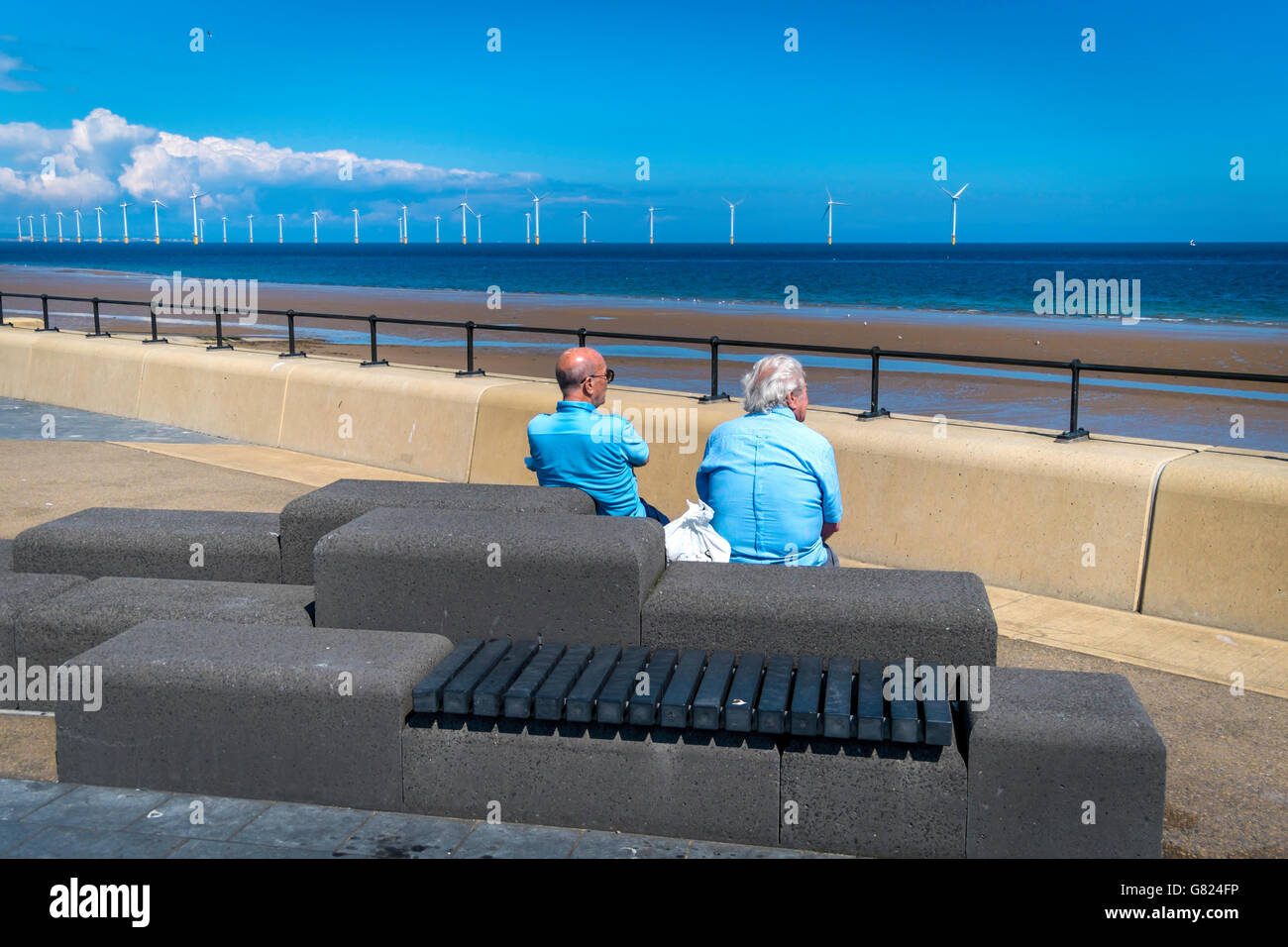 Two senior men sitting on the Redcar Promenade looking out to sea on a ...