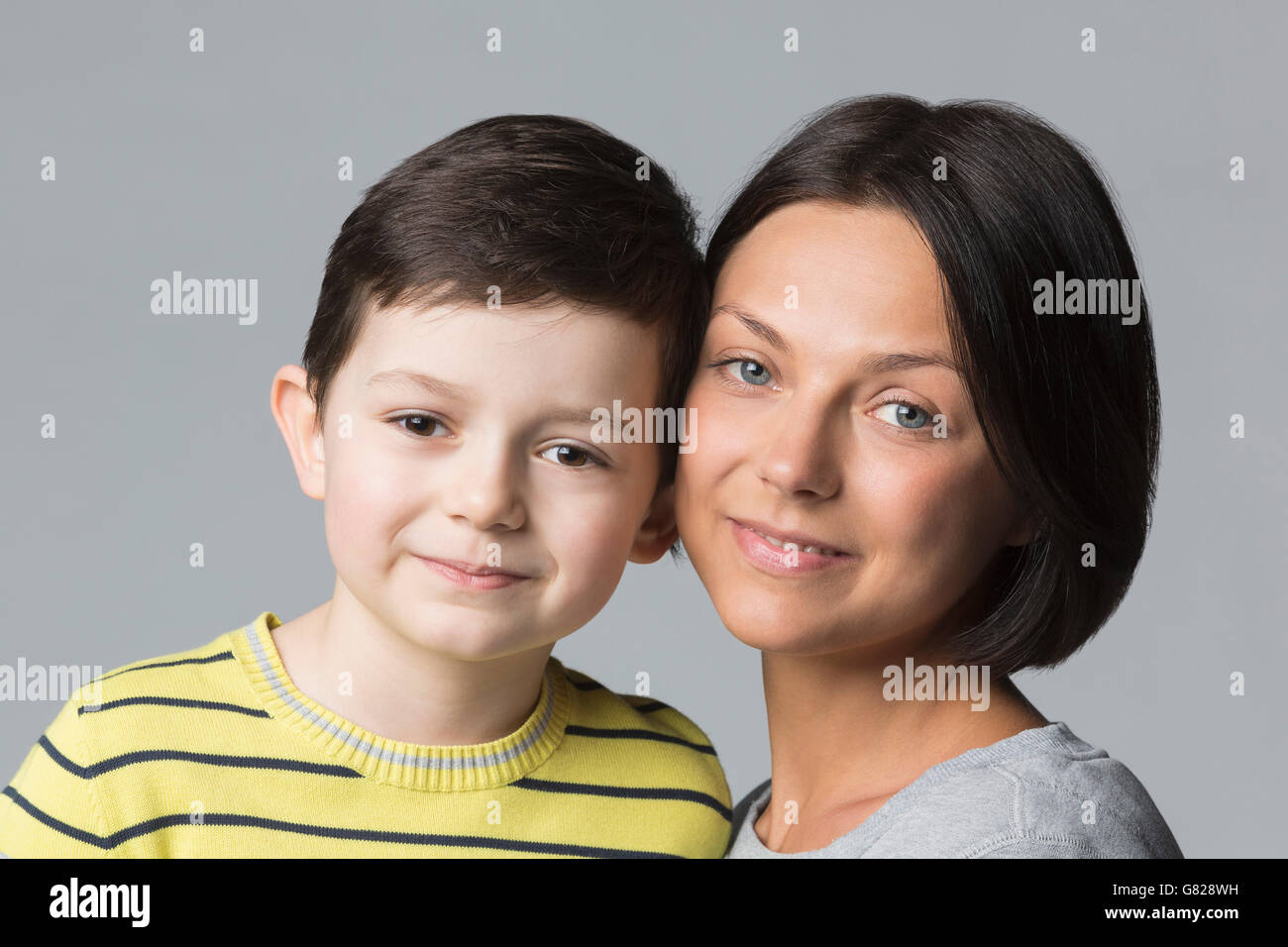Portrait of smiling boy with mother against gray background Stock Photo ...