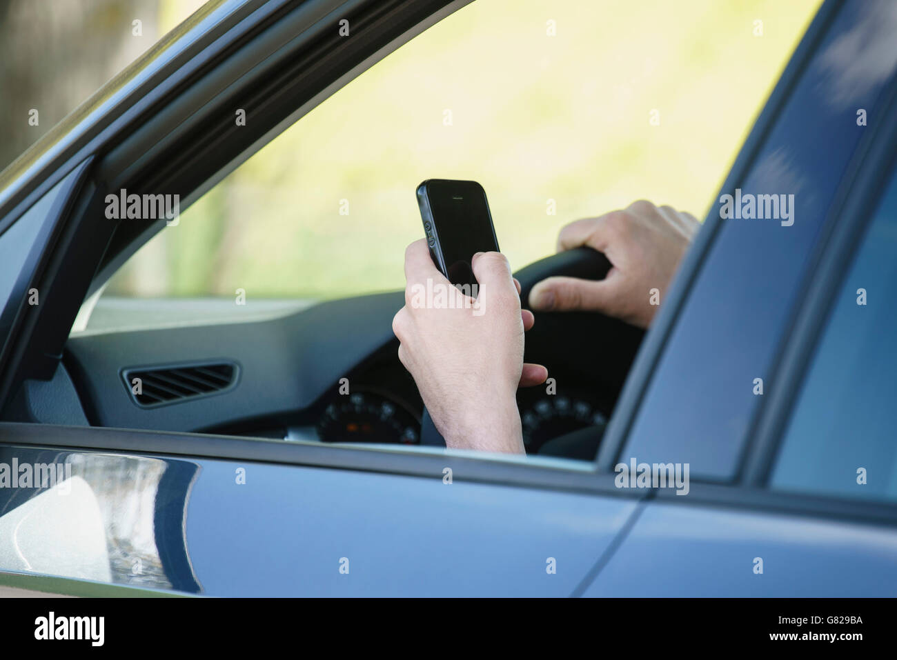 Cropped image of hand using mobile phone in car Stock Photo - Alamy