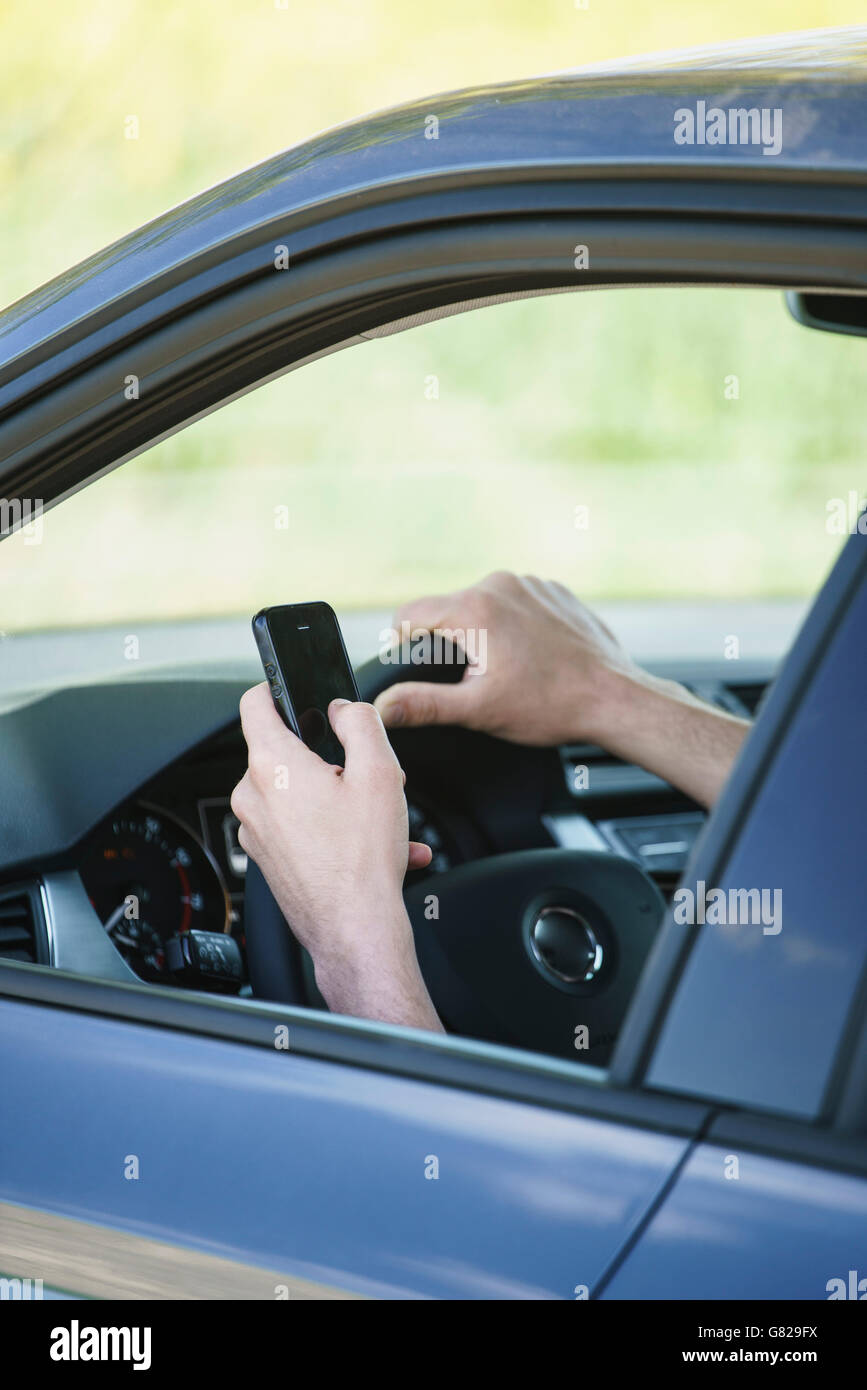 Cropped image of hand using smart phone in car Stock Photo - Alamy