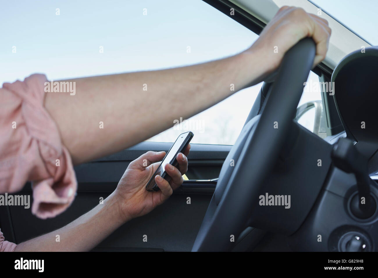 Cropped image of hand using phone while driving car Stock Photo - Alamy