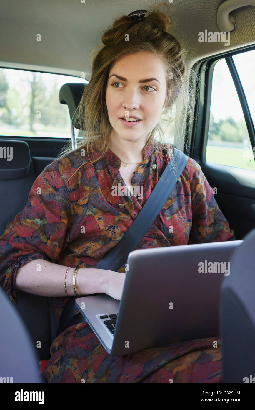 Thoughtful young woman using laptop in car Stock Photo - Alamy