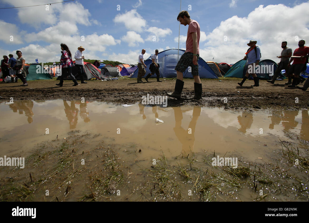 Festivalgoers walking past a pool of mud in a campsite at the Isle of ...