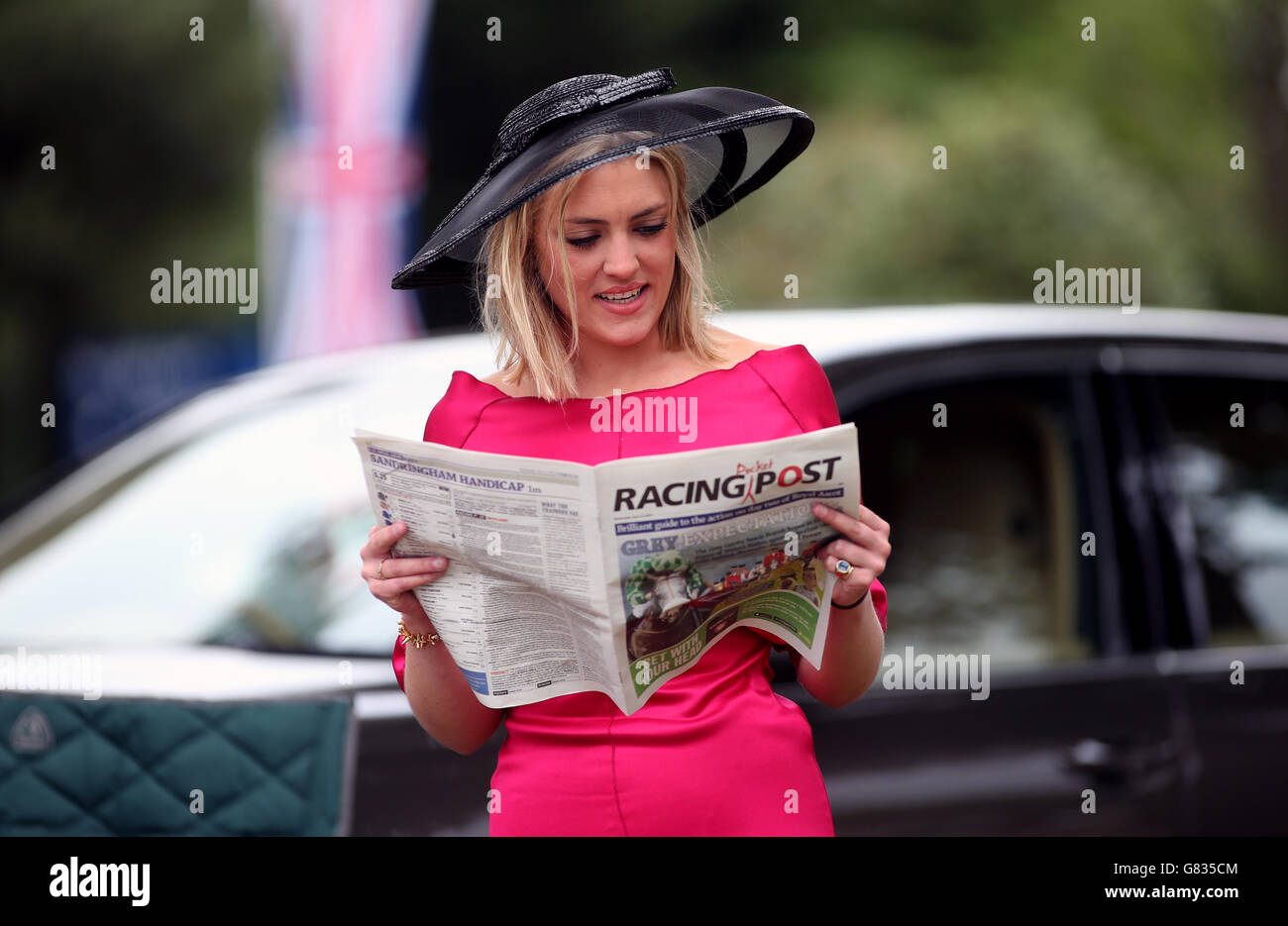 A racegoer checks the race cards and form in the Racing Post newspaper ...