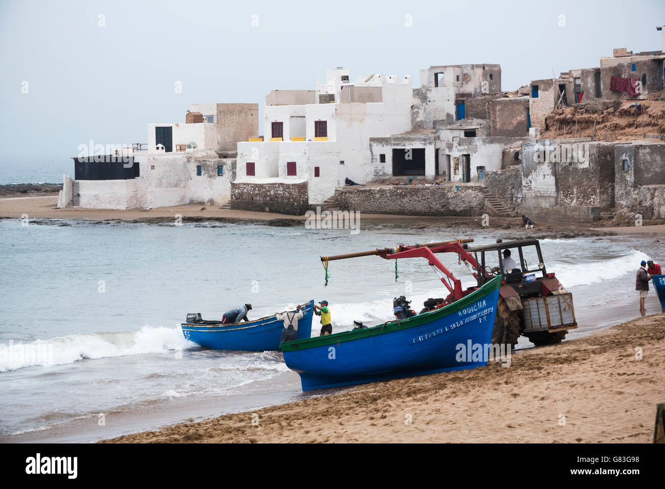 A tractor helps lift fishermen's boats ashore in Tifnit beach near ...