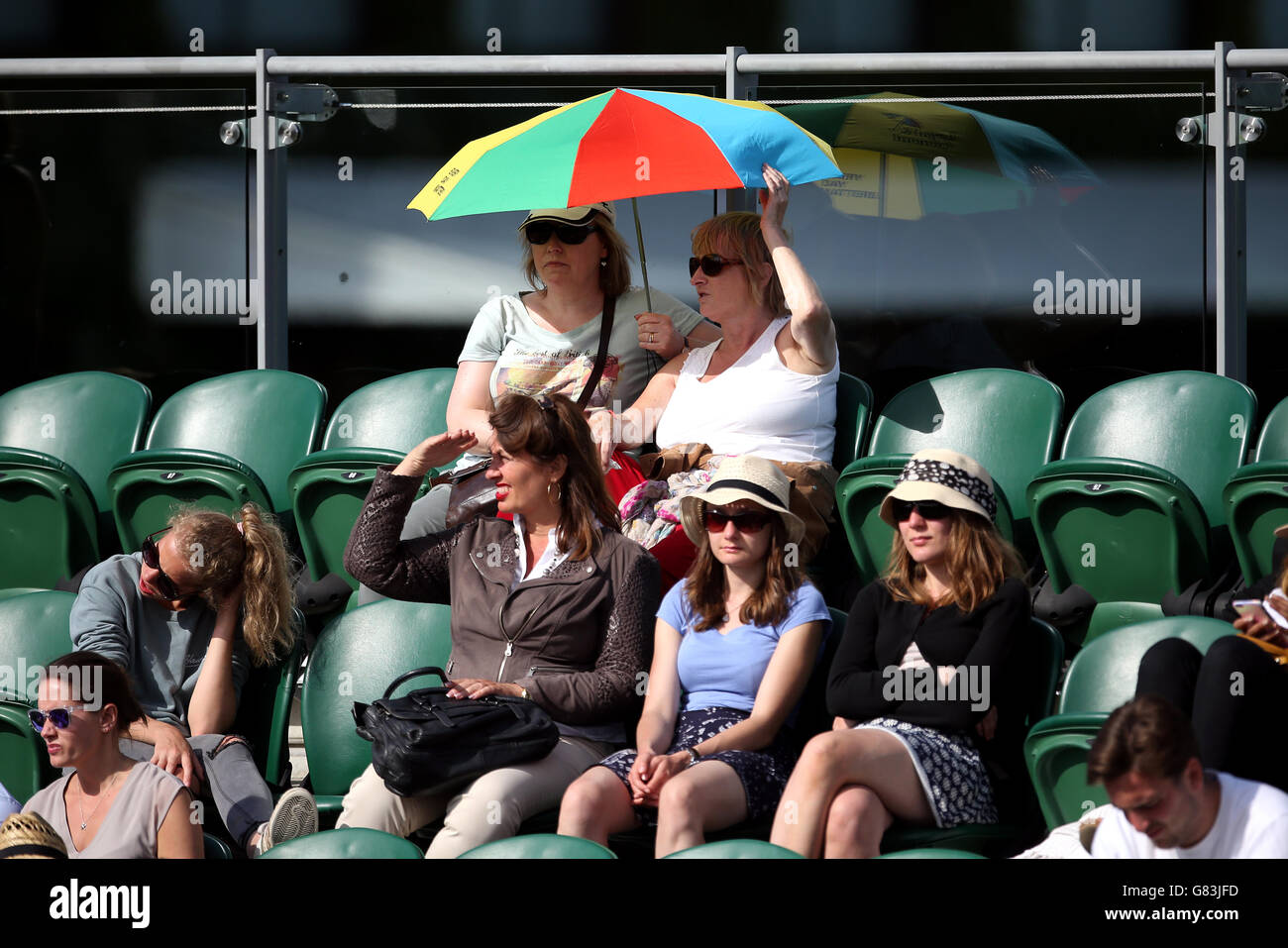 Spectators shelter under an umbrella from the sun on day One of the ...