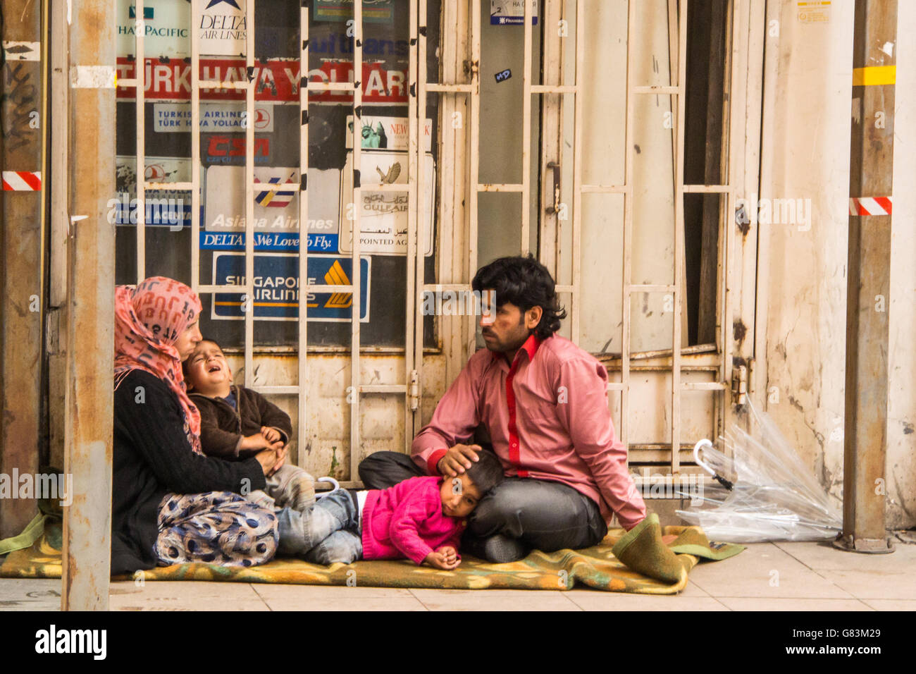 Homeless Syrian family sitting on sidewalk in front of travel agency in ...