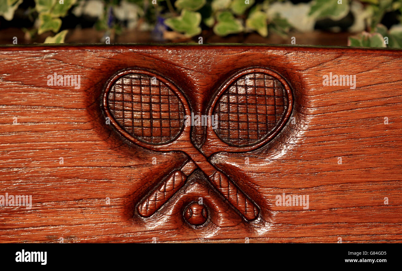 Detail of a tennis racket and ball carved into a bench during day ...