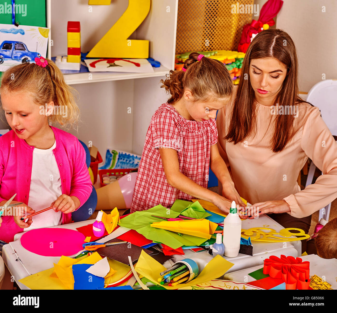 Kids holding colored paper on table in kindergarten Stock Photo - Alamy
