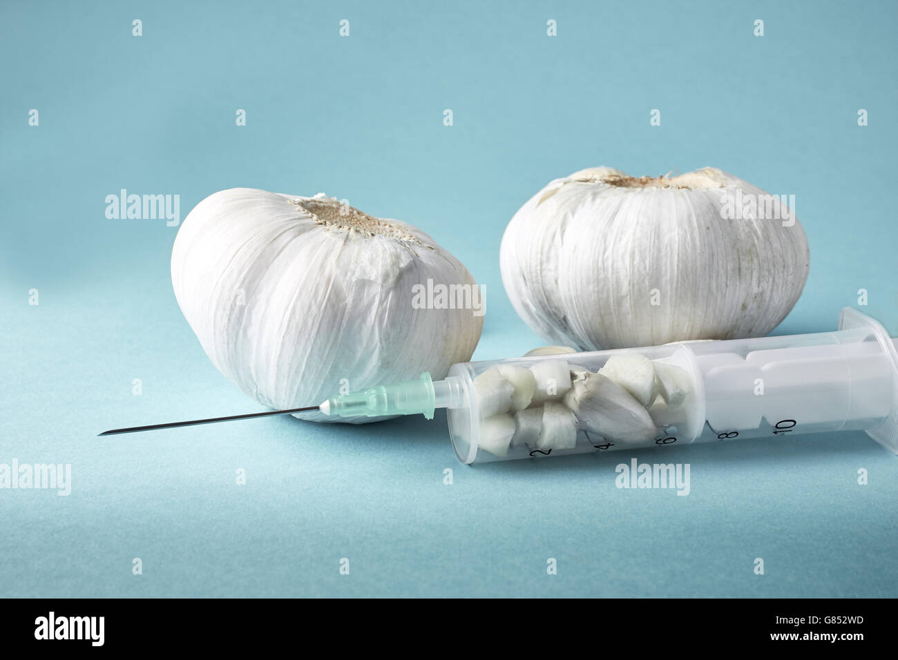 Injection with needle filled with garlic on green background. Concept ...