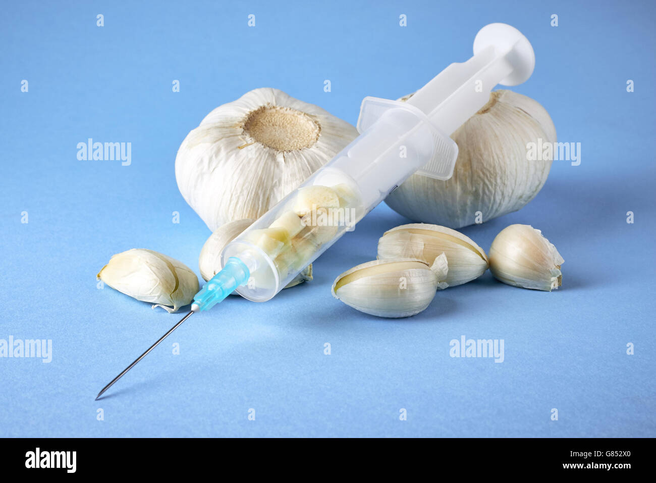 Injection with needle filled with garlic on blue background. Concept ...