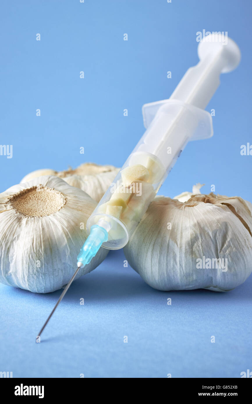 Injection with needle filled with garlic on blue background. Concept ...