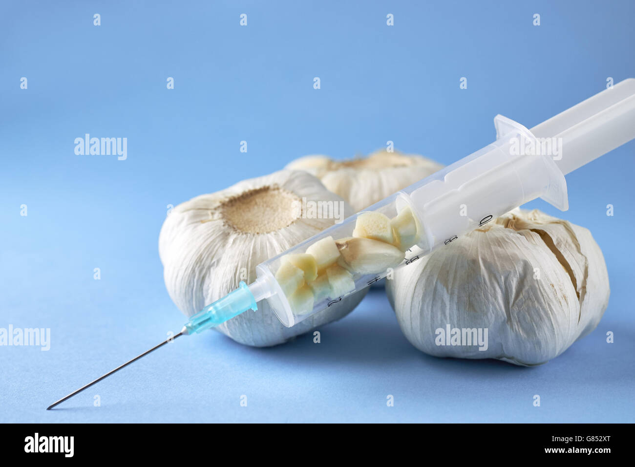 Injection with needle filled with garlic on blue background. Concept ...