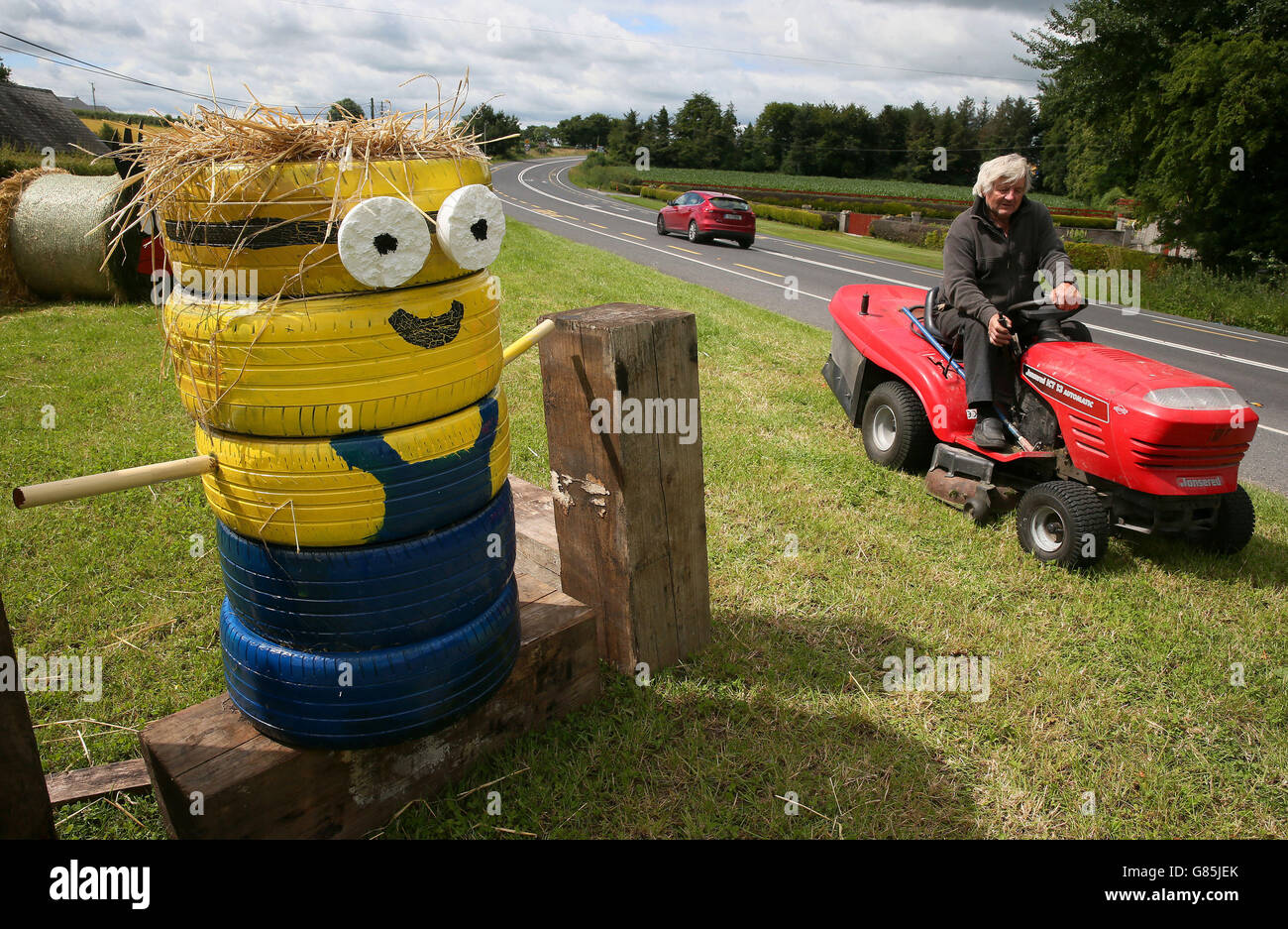 Billy Barry cuts the grass beside a 'Minions' scarecrow during the ...