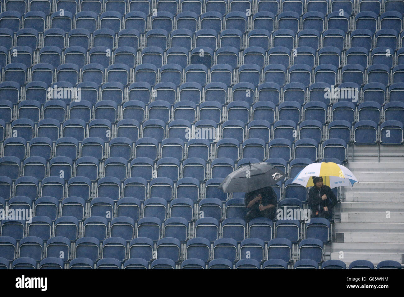 Golf fans shelter from the elements under umbrellas in the stands ...