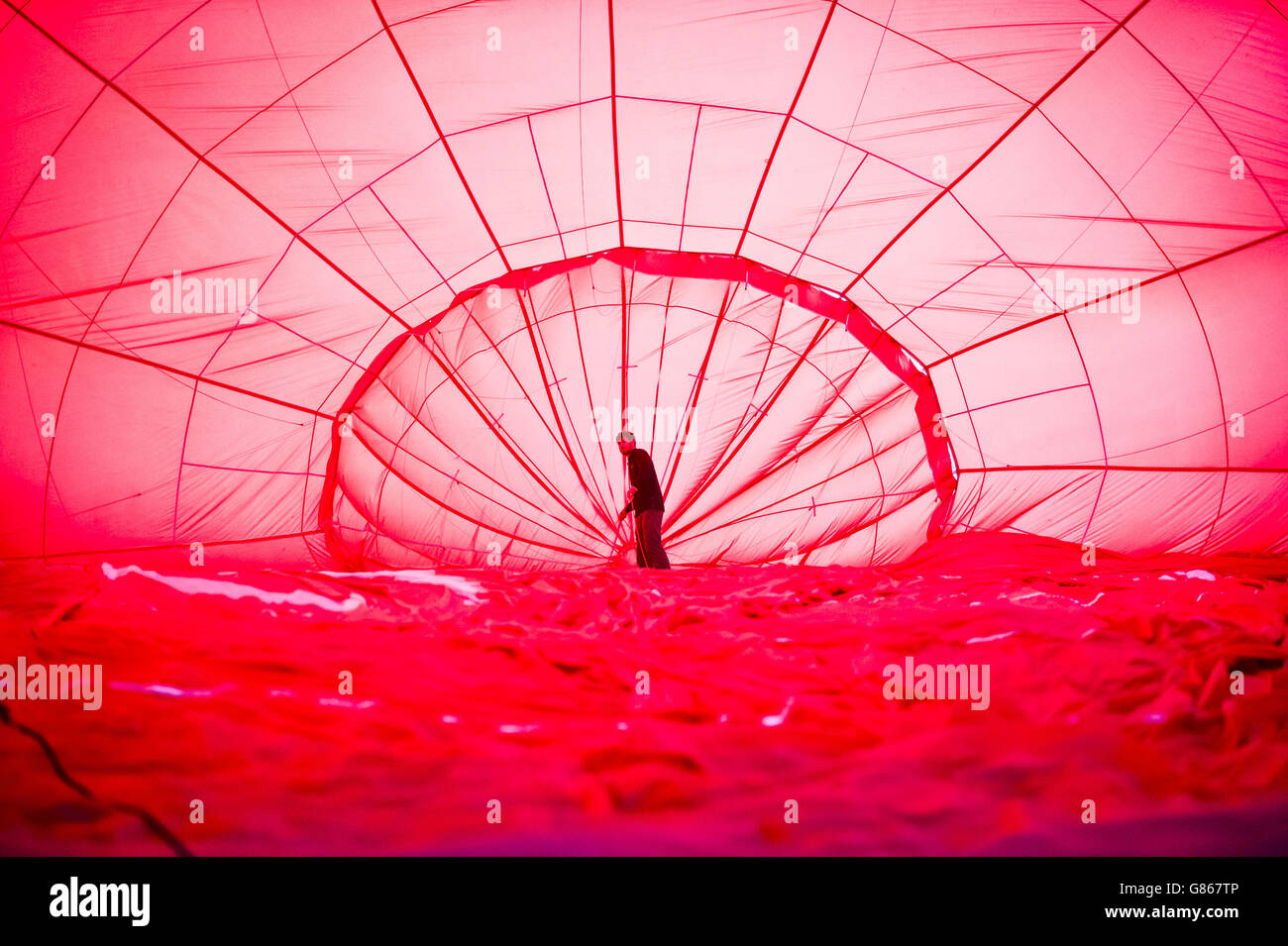 A hot air balloon crew member checks rigging before the first mass ...