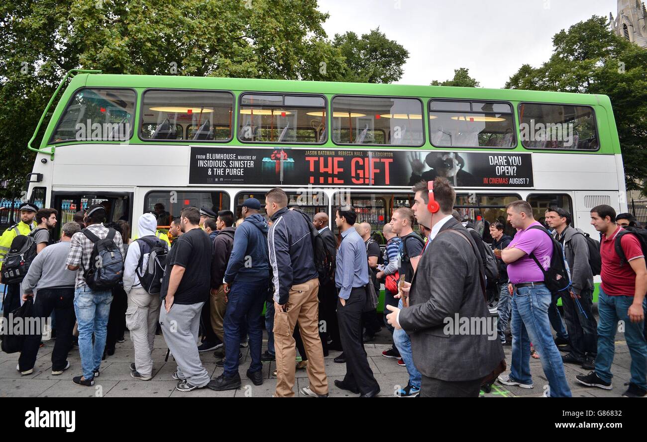People queue for a bus at Stratford station, London, as commuters and ...